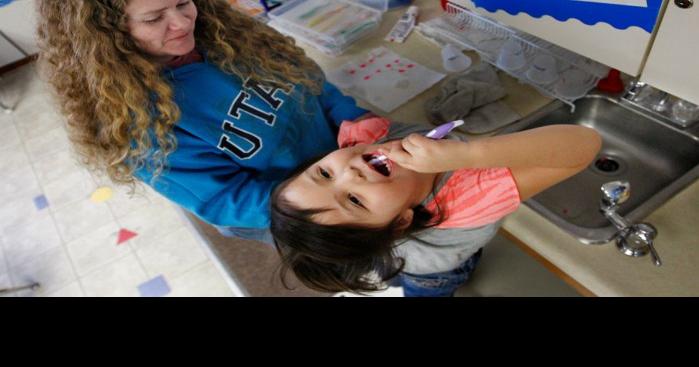 Kristi Dorn helps Amari Iron brush her teeth