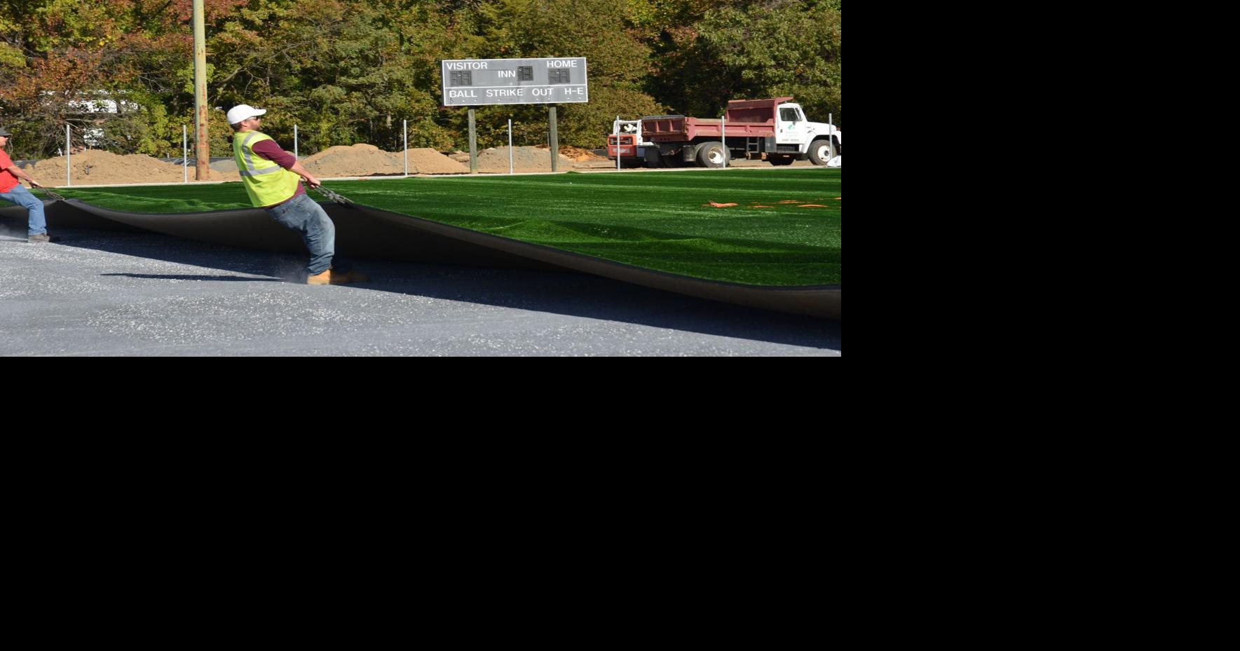 Synthetic turf rolled out and installed during athletic field ...