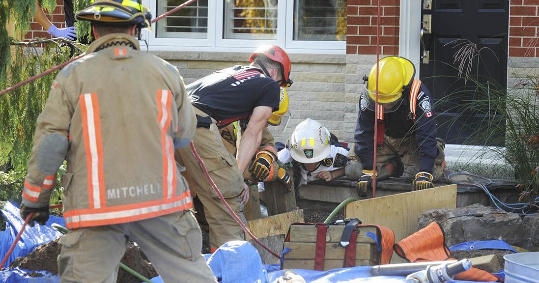 Emergency workers digging to free man trapped in trench in downtown ...