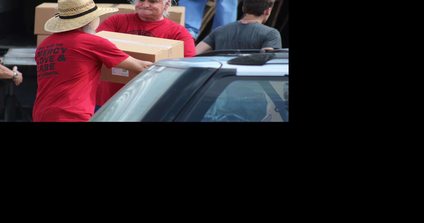Pulling together: Volunteers hand out food boxes at giveaway | News ...