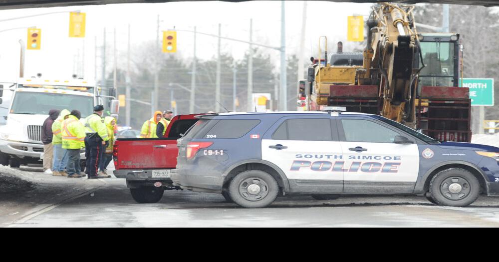Truck with tall load wedged under bridge