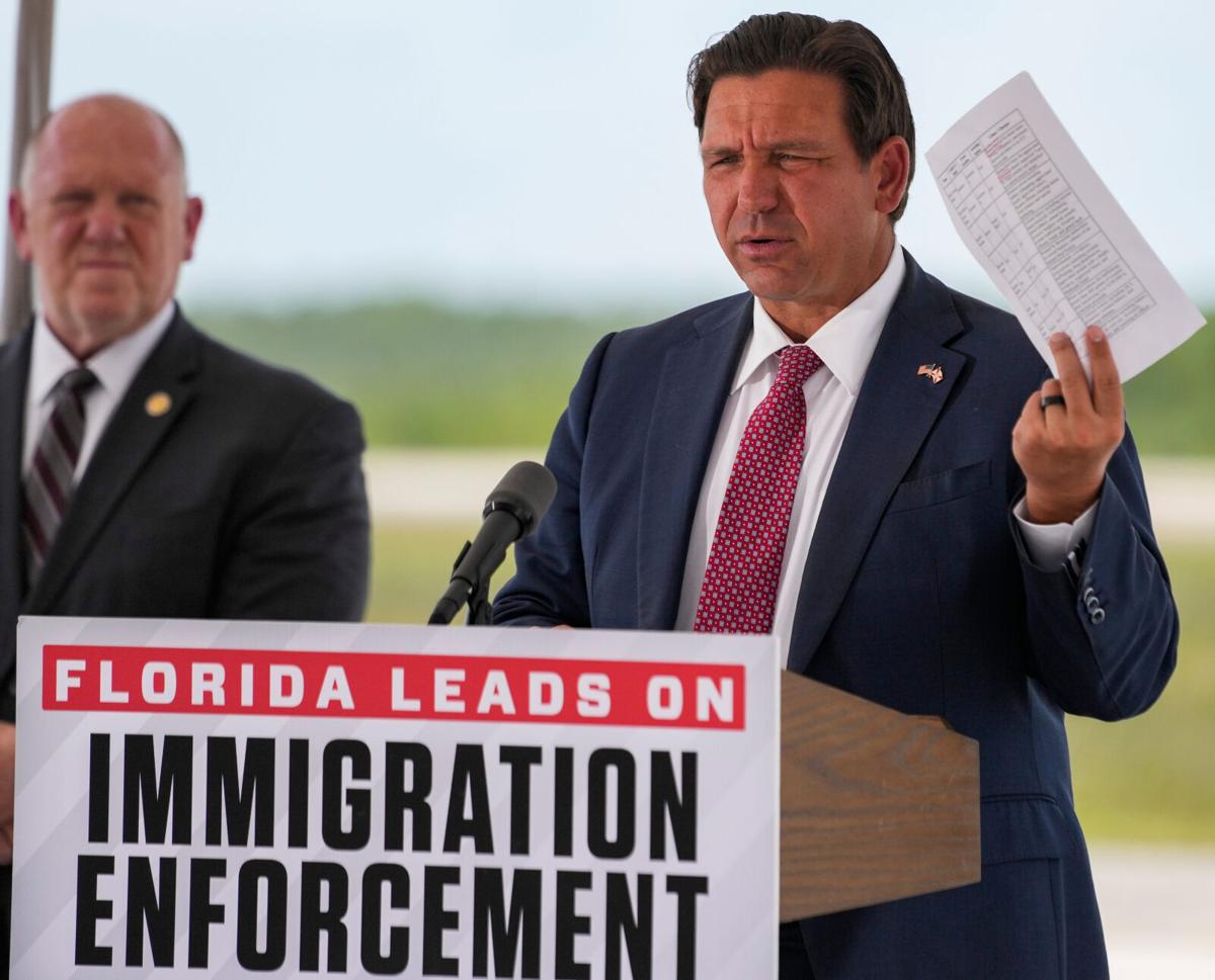 Governor Ron DeSantis holds up a sheet with crimes committed by ...