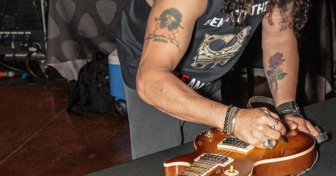 Slash autographs iconic guitar at Hard Rock