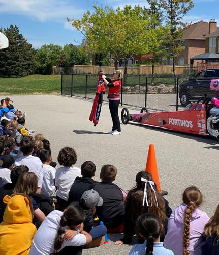 Female race track driver inspiring school children