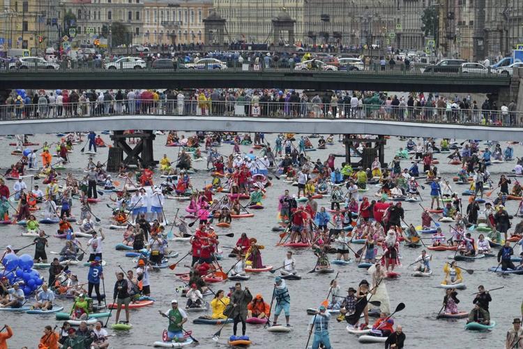 Photos show costumed participants steer stand-up paddle boards at a ...
