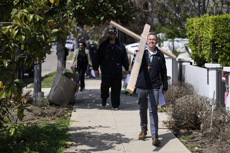 Members of burned LA church bear a cross through their devastated ...
